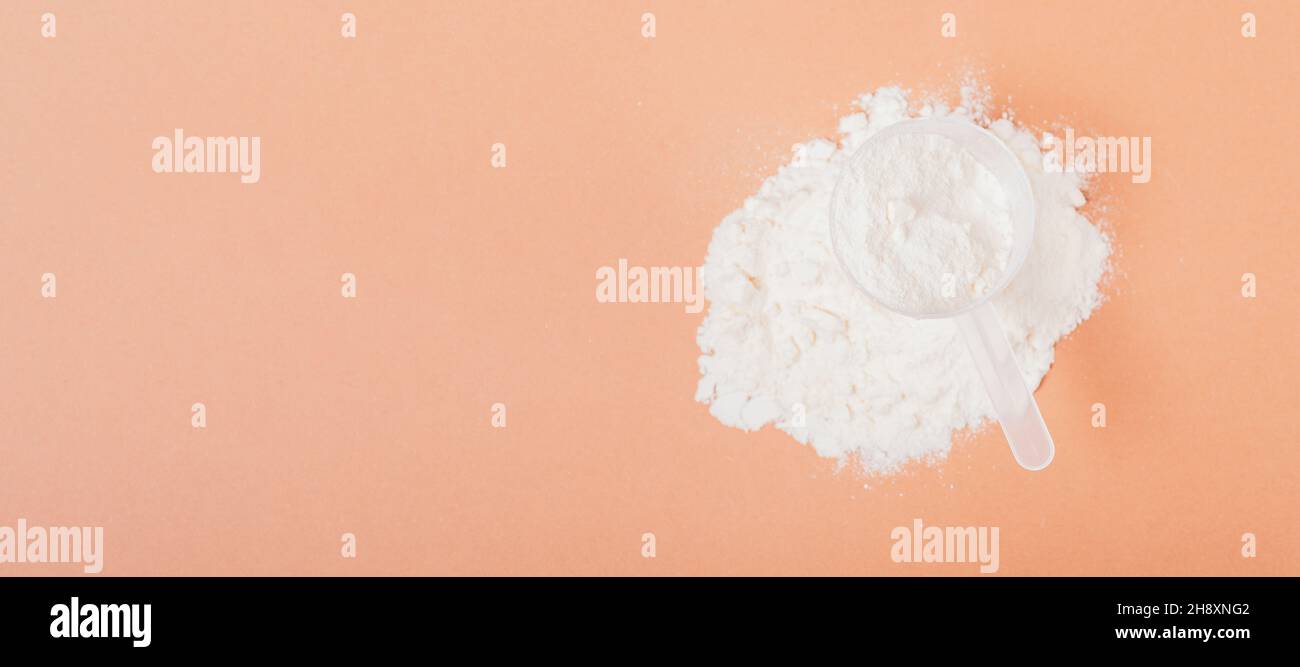 Top view protein powder heap with measuring scoop on light brown ...