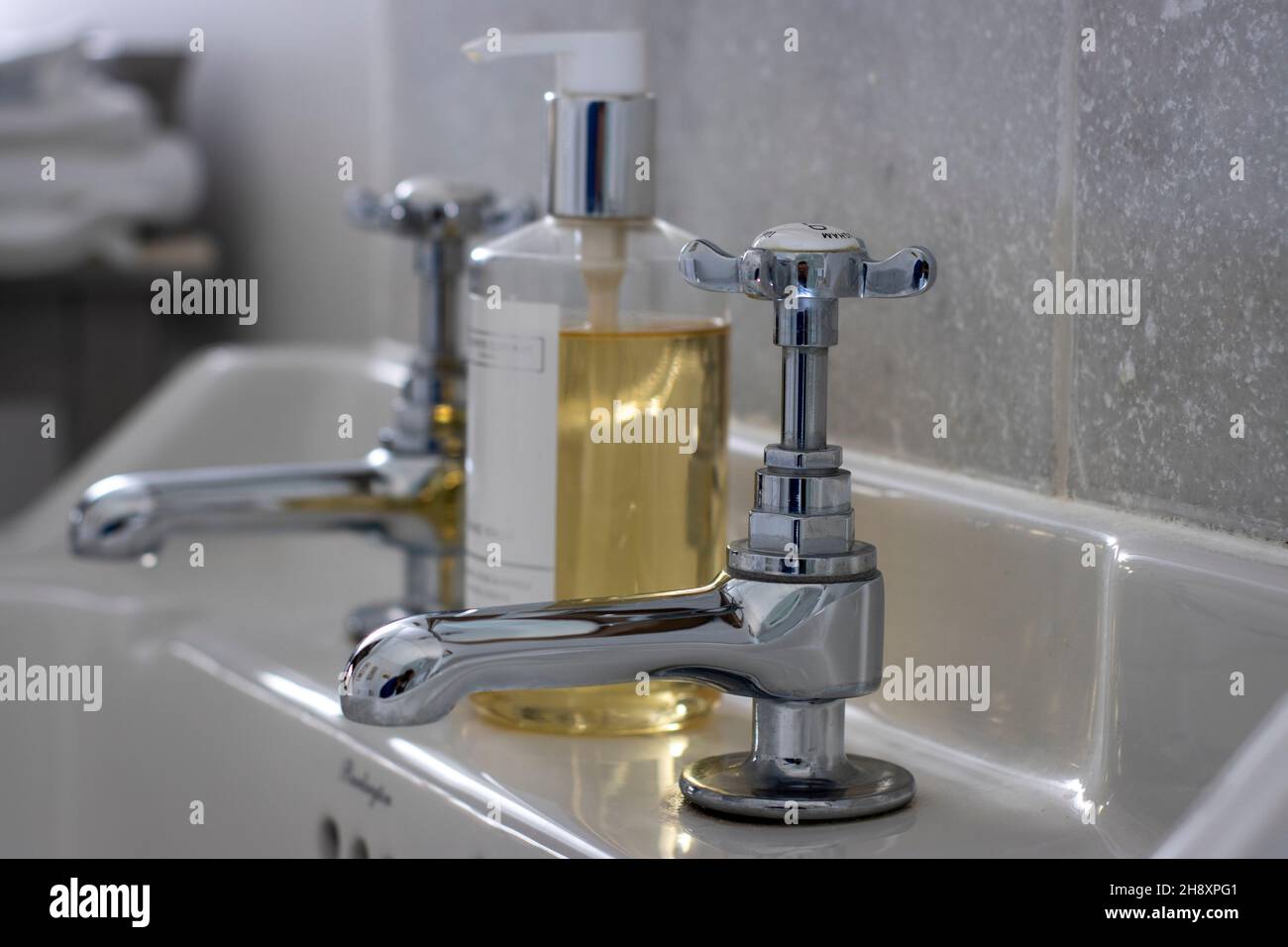 Chrome bathroom taps and some liquid hand soap Stock Photo - Alamy