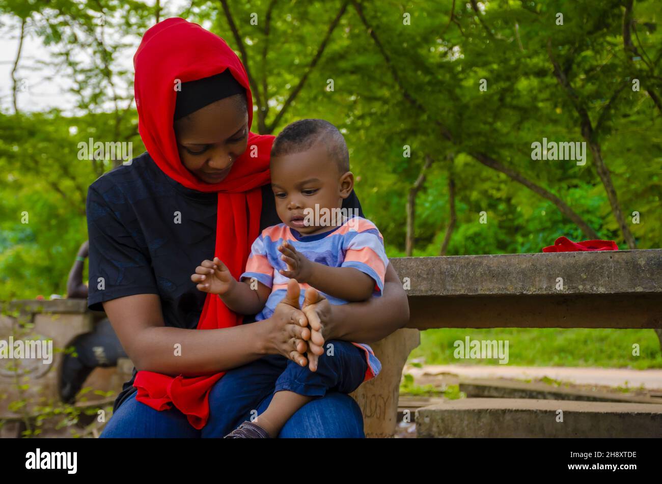 African mother with her child sitting on a bench in a park Stock Photo ...