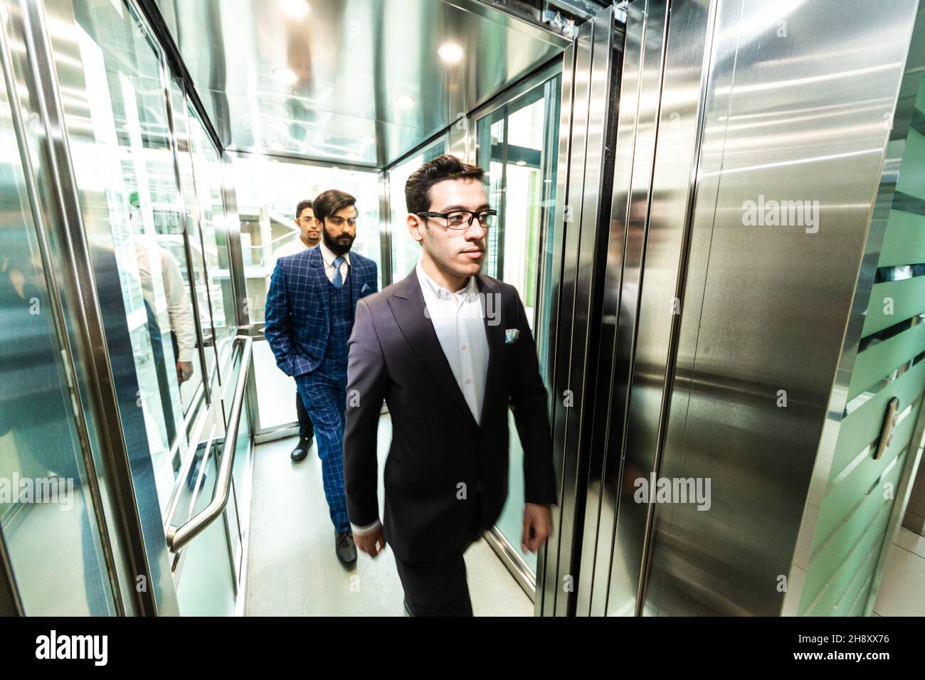 Business team group going on elevator. Business people in a large glass elevator in a modern ...
