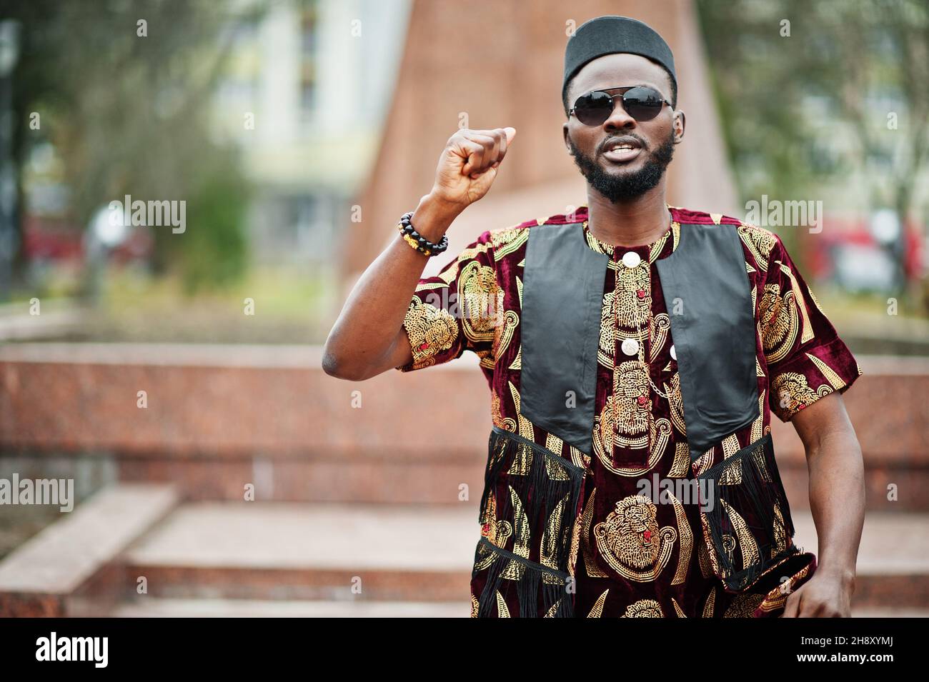 African stylish and handsome man in traditional outfit and black cap ...
