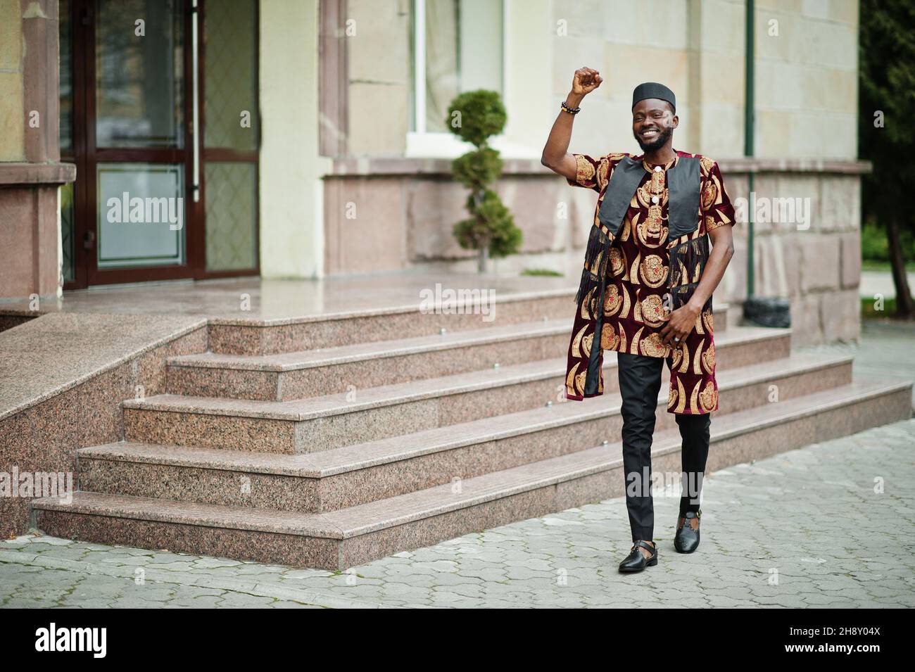 African stylish and handsome man in traditional outfit and black cap ...