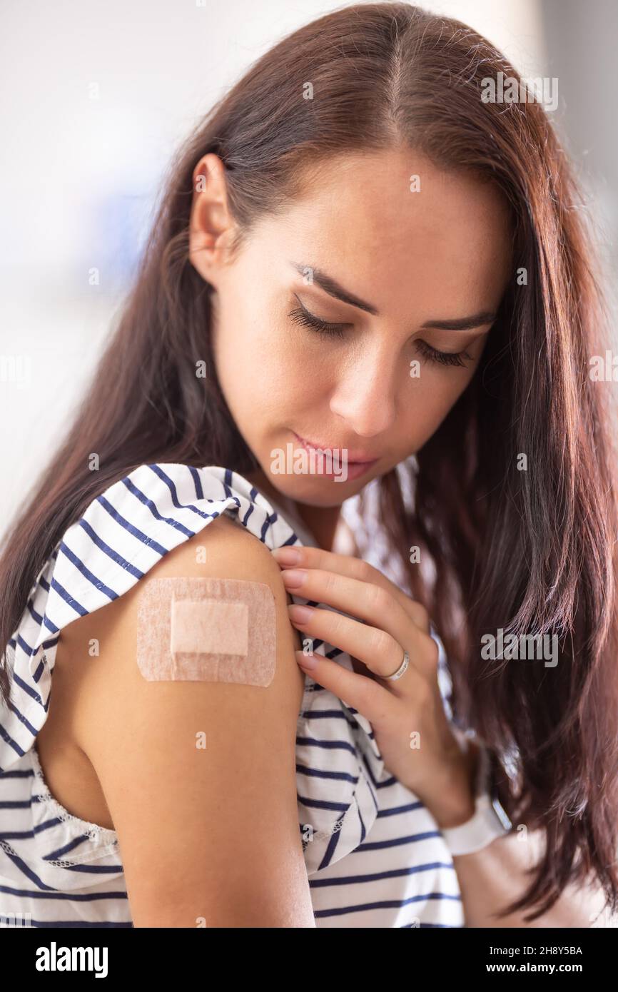 Vaccinated female looks at the plaster on her right shoulder Stock ...