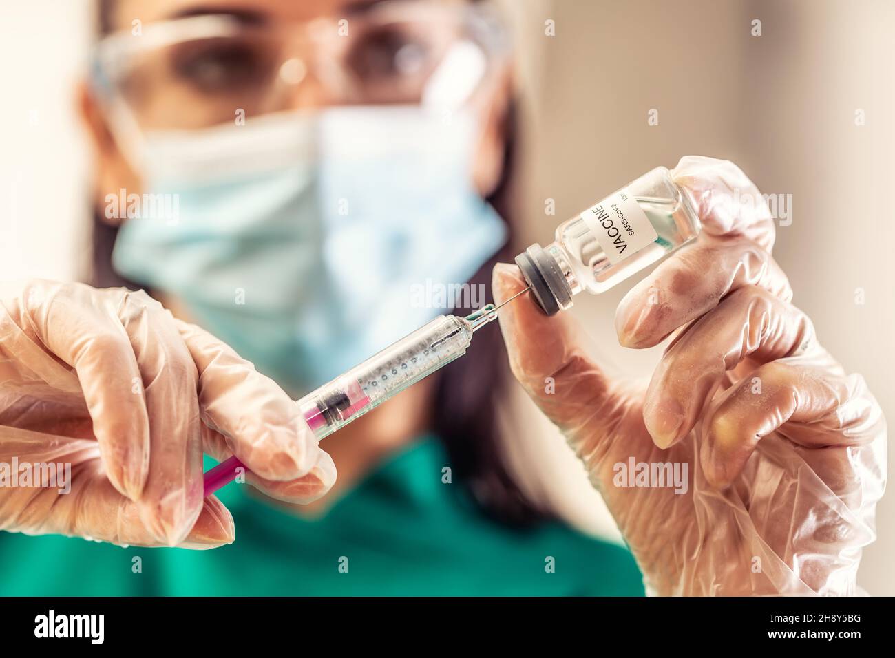 Doctor wearing personal protective equipment takes a dose of SARS CoV-2 ...