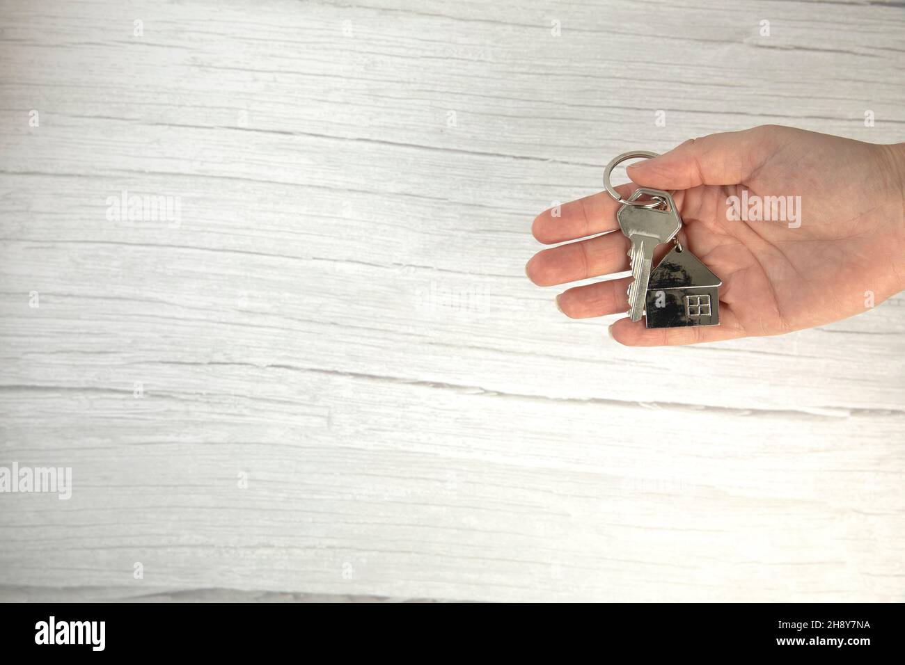 realtor female hand holding new door key to new house on white ...
