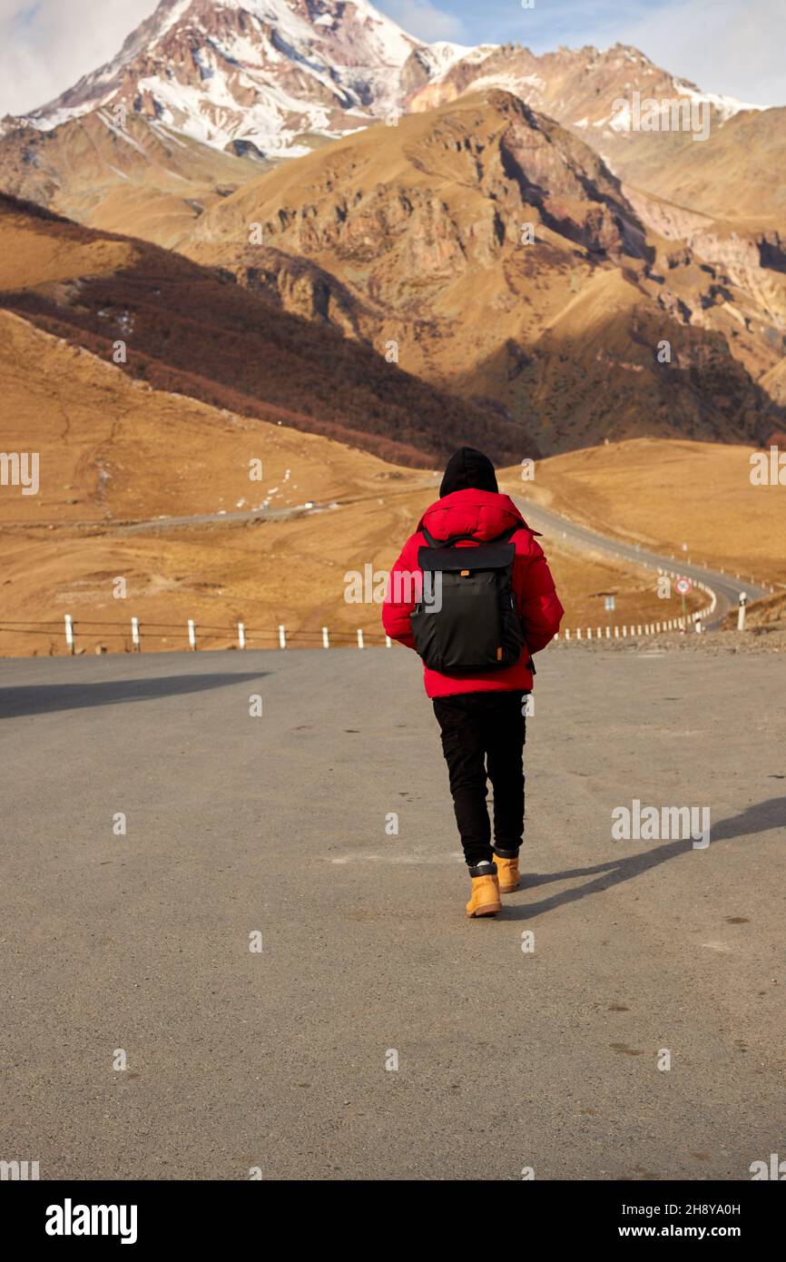 Back view of traveler with backpack hiking alone in mountainous region ...