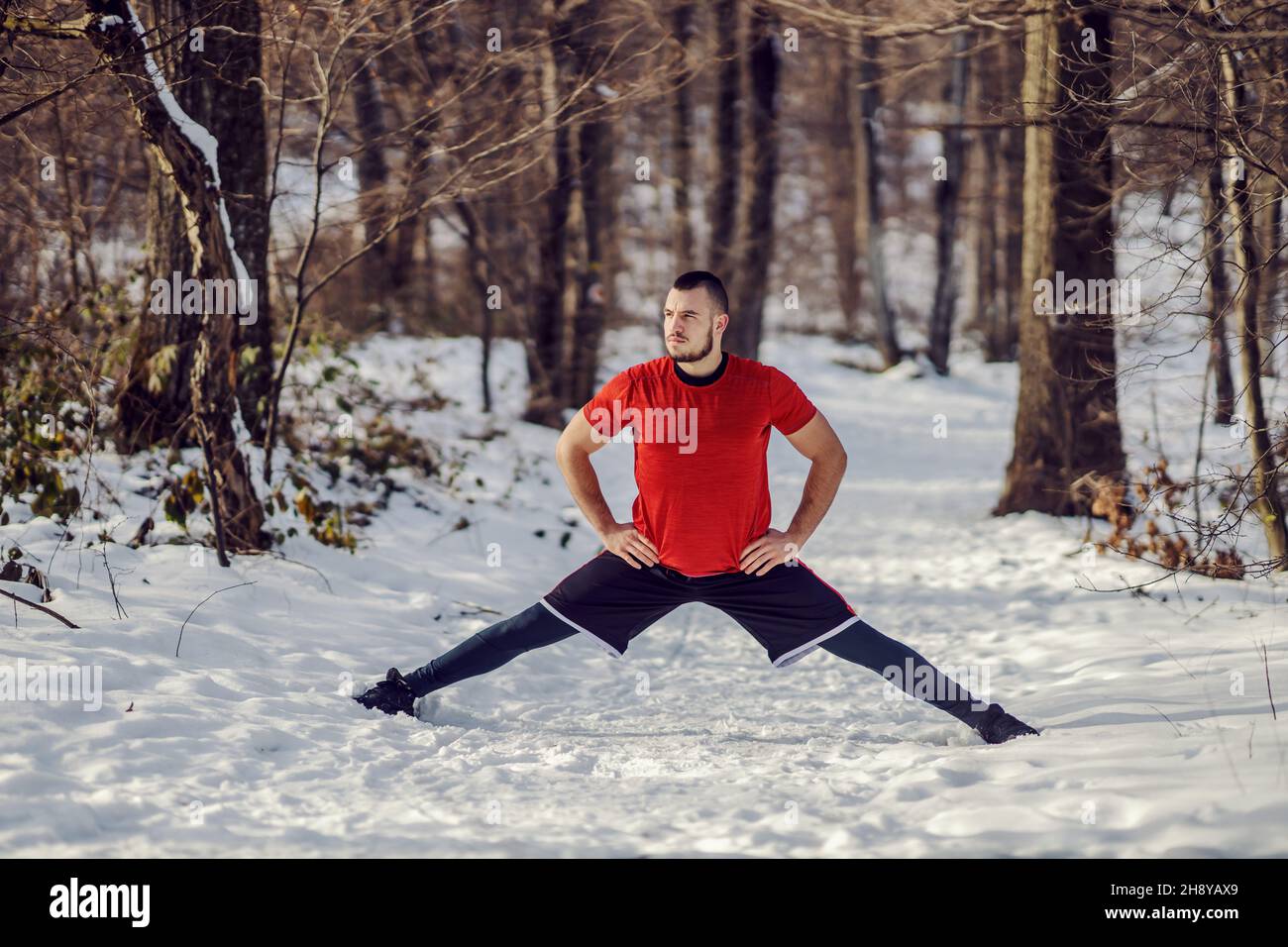 Sportsman doing splits and stretching exercises while standing in ...