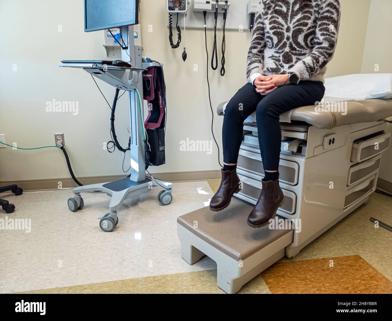 Inside of an exam room with a bed, some medical devices, a computer. A ...