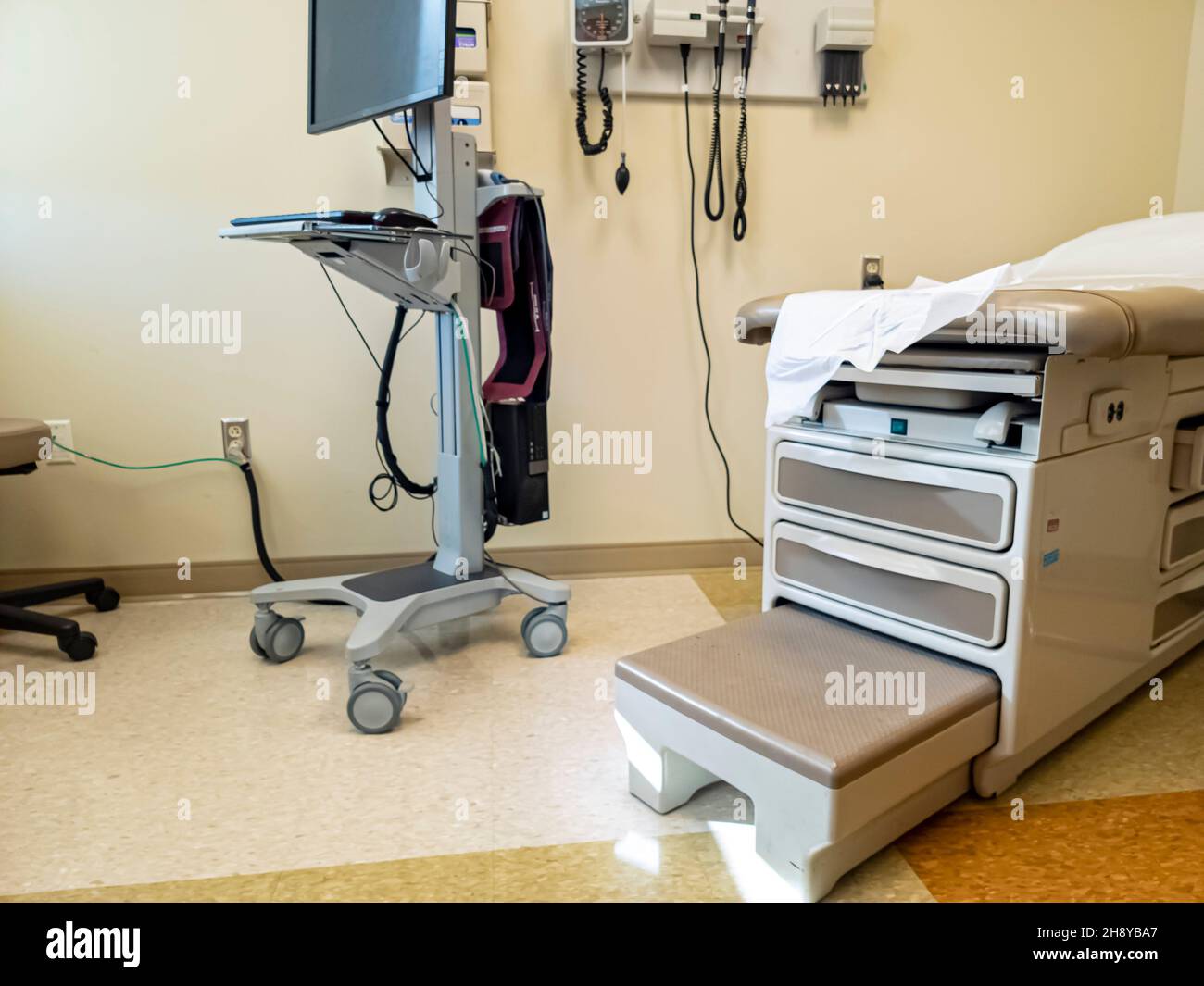 Inside of an empty exam room with a bed, some medical devices, a ...