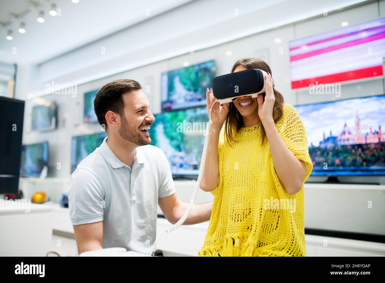Pretty young couple is testing VR headset in the electronics store ...
