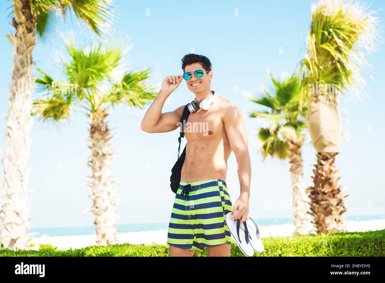 Handsome guy in cool beach outfit smiling walking down seaside to ...