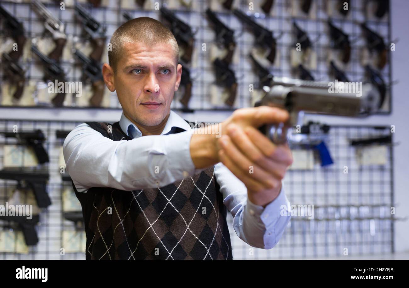 Man takes aim with a revolver when choosing in gun store Stock Photo ...
