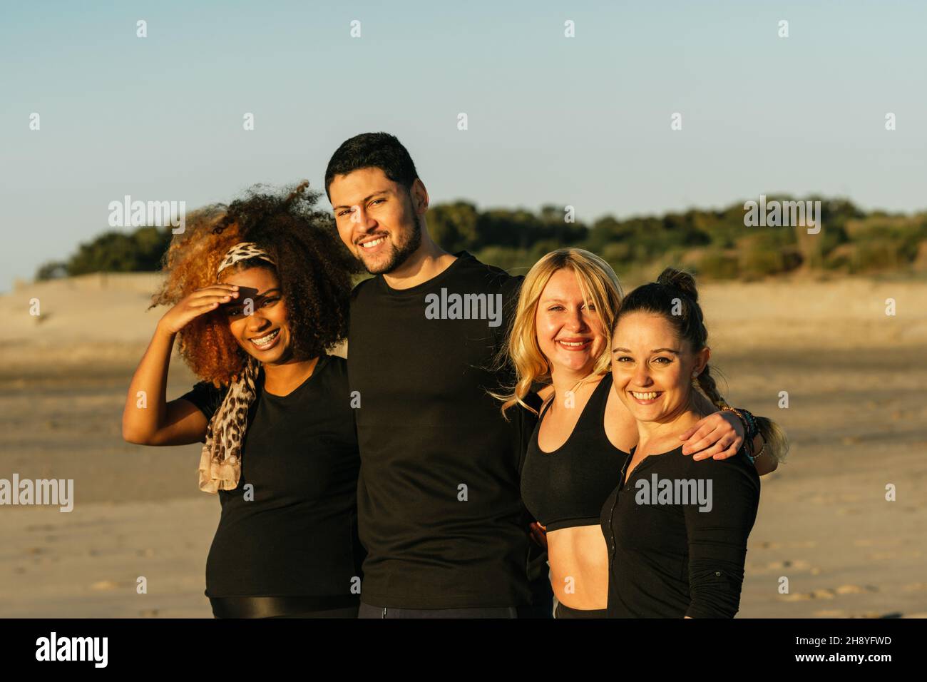 Multicultural yoga class group standing facing the camera outdoors ...