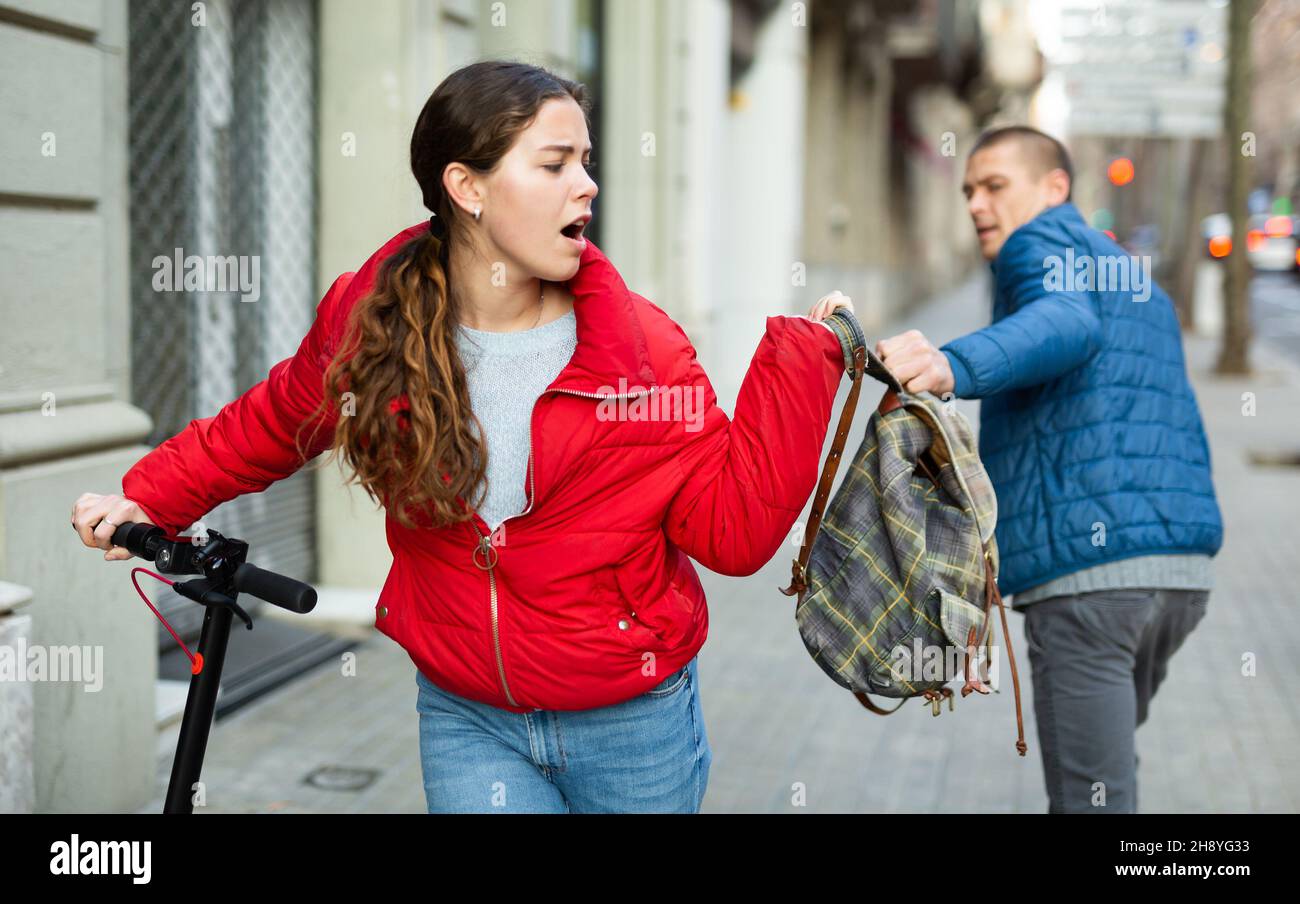 Male thief stealing bagback from scared woman Stock Photo - Alamy