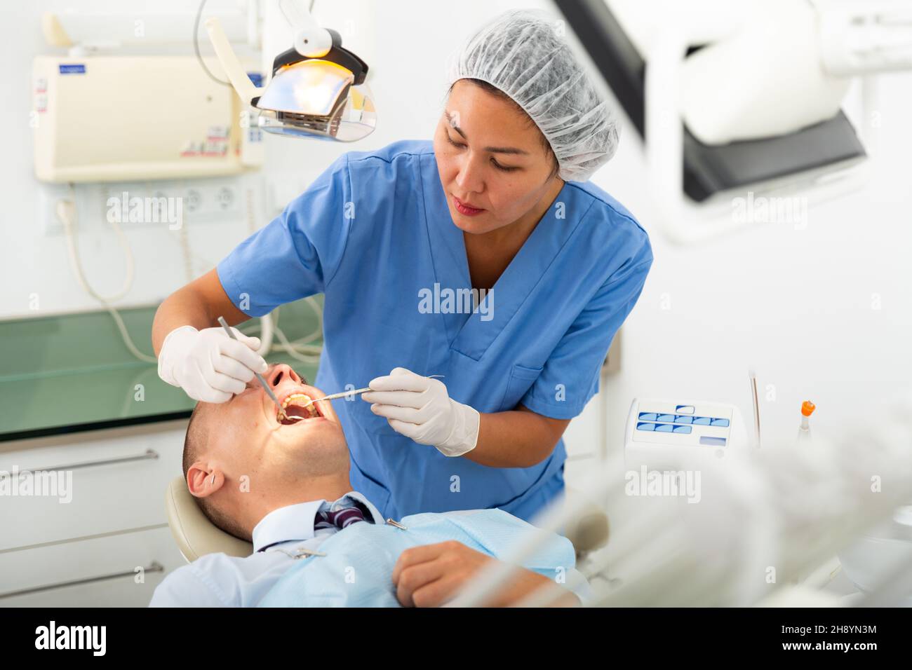 Dentist professional filling teeth for man patient sitting in chair ...