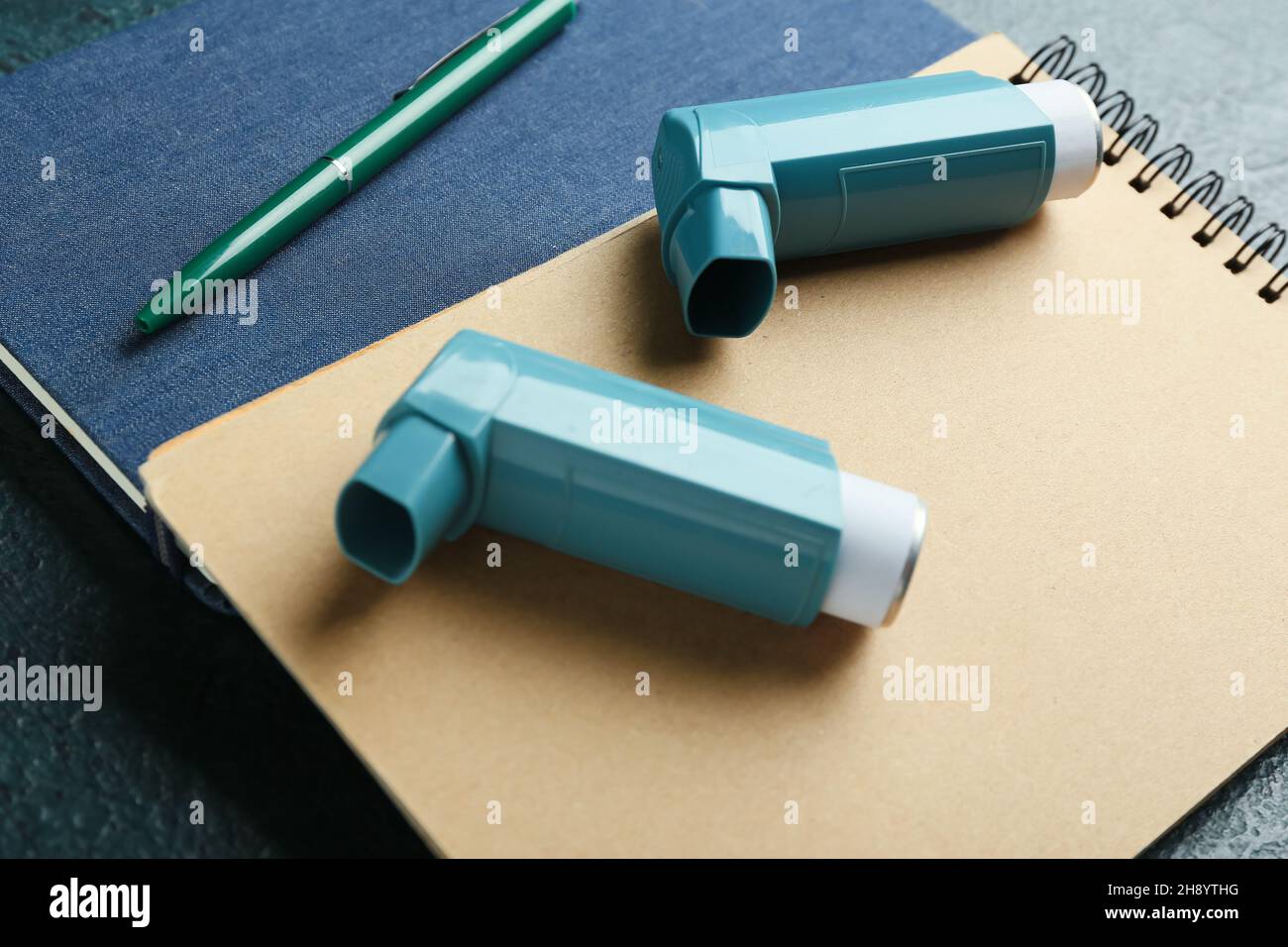 Asthma inhalers, pen and notebooks on table, closeup Stock Photo - Alamy