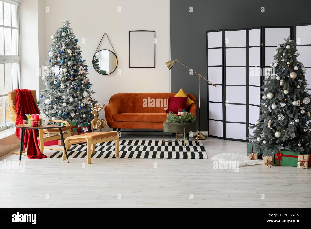 Interior of festive living room with red sofa, Christmas trees and ...