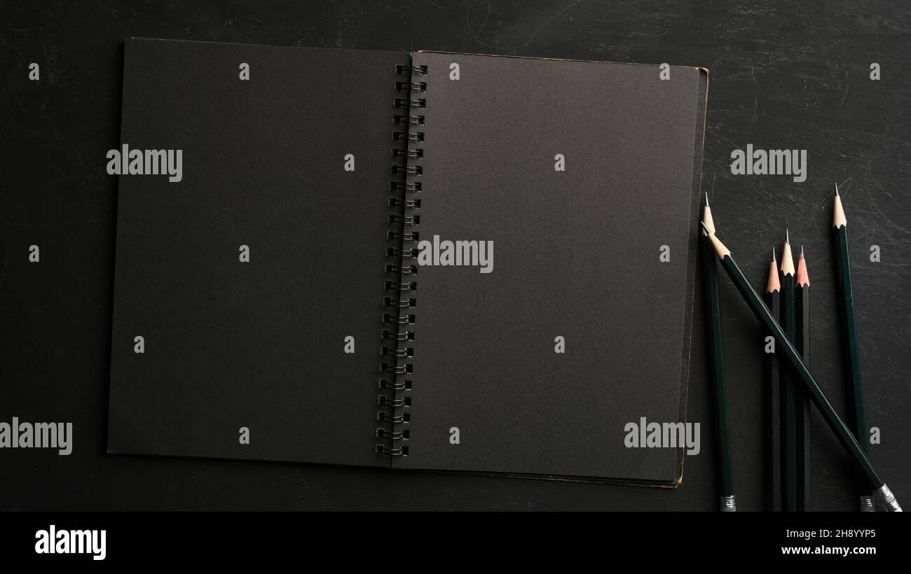 Empty modern black notebook with black papers and pencils on modern ...
