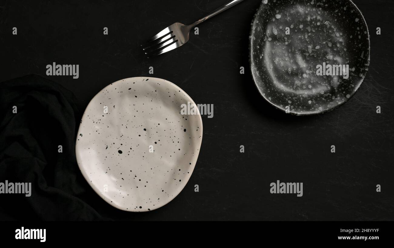 Handmade craft ceramic plates set with fork on black background ...