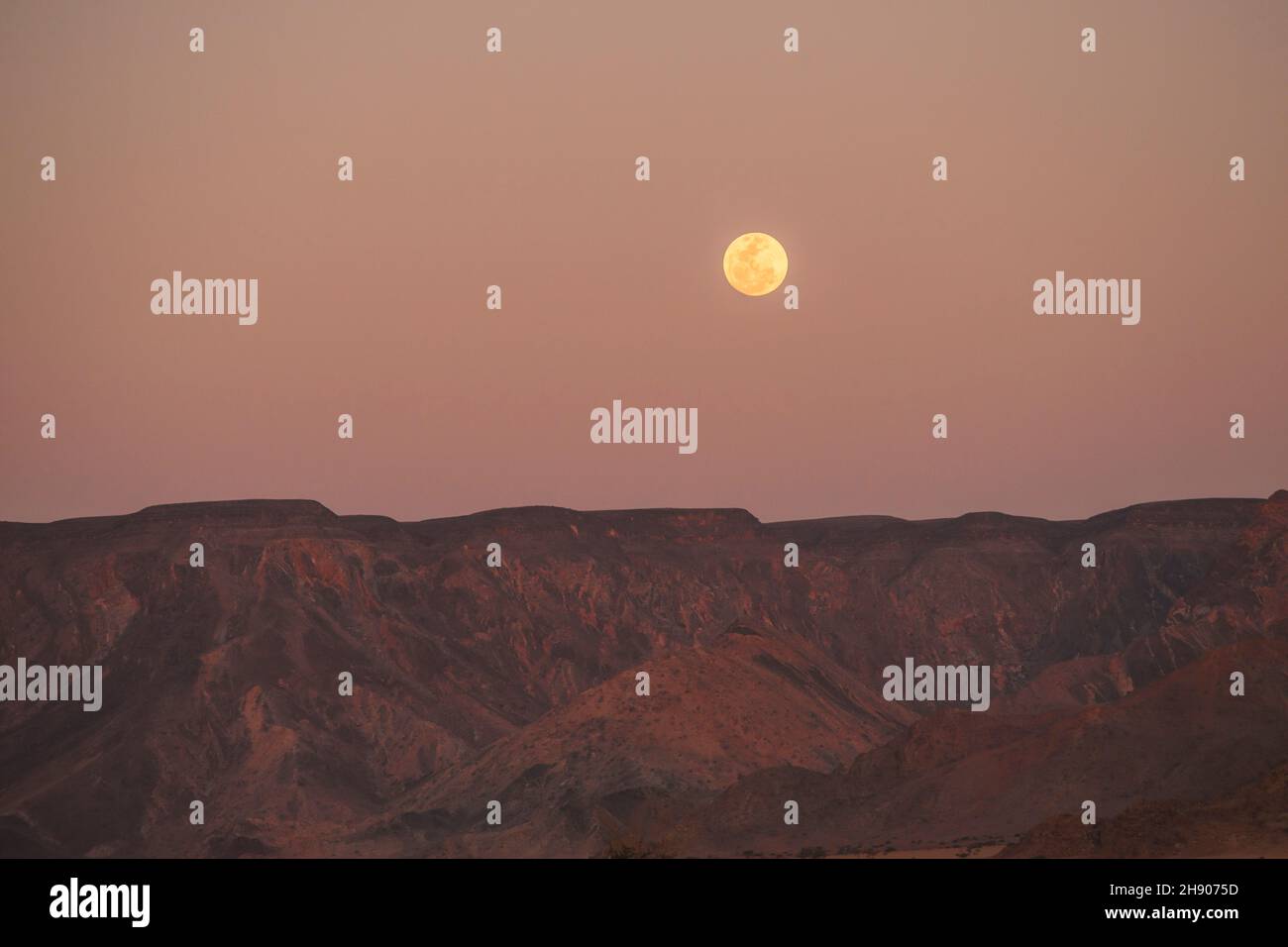 full moon above rocky mountain ridge in desert of Namibia Stock Photo ...