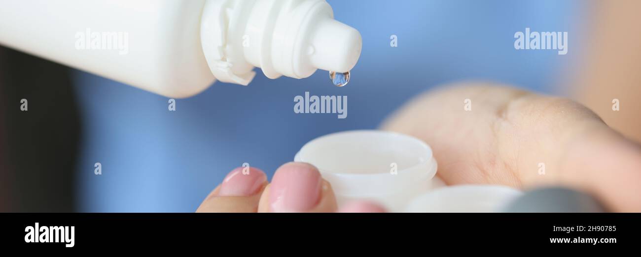 Woman pouring lens solution from bottle into plastic container closeup ...
