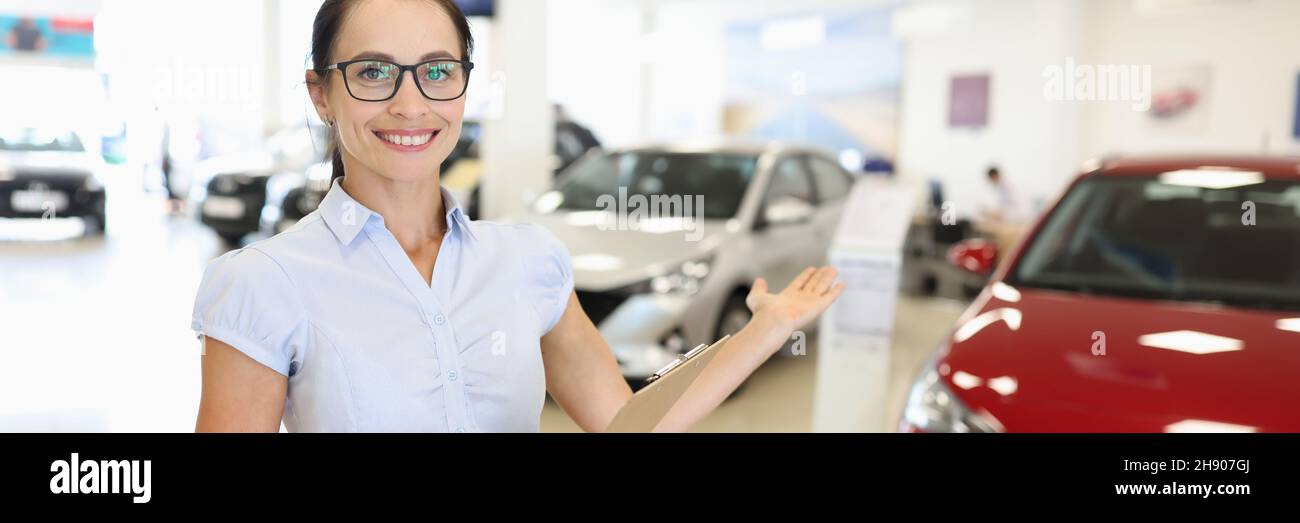 Woman salesman with clipboard in her hands showing new car in ...