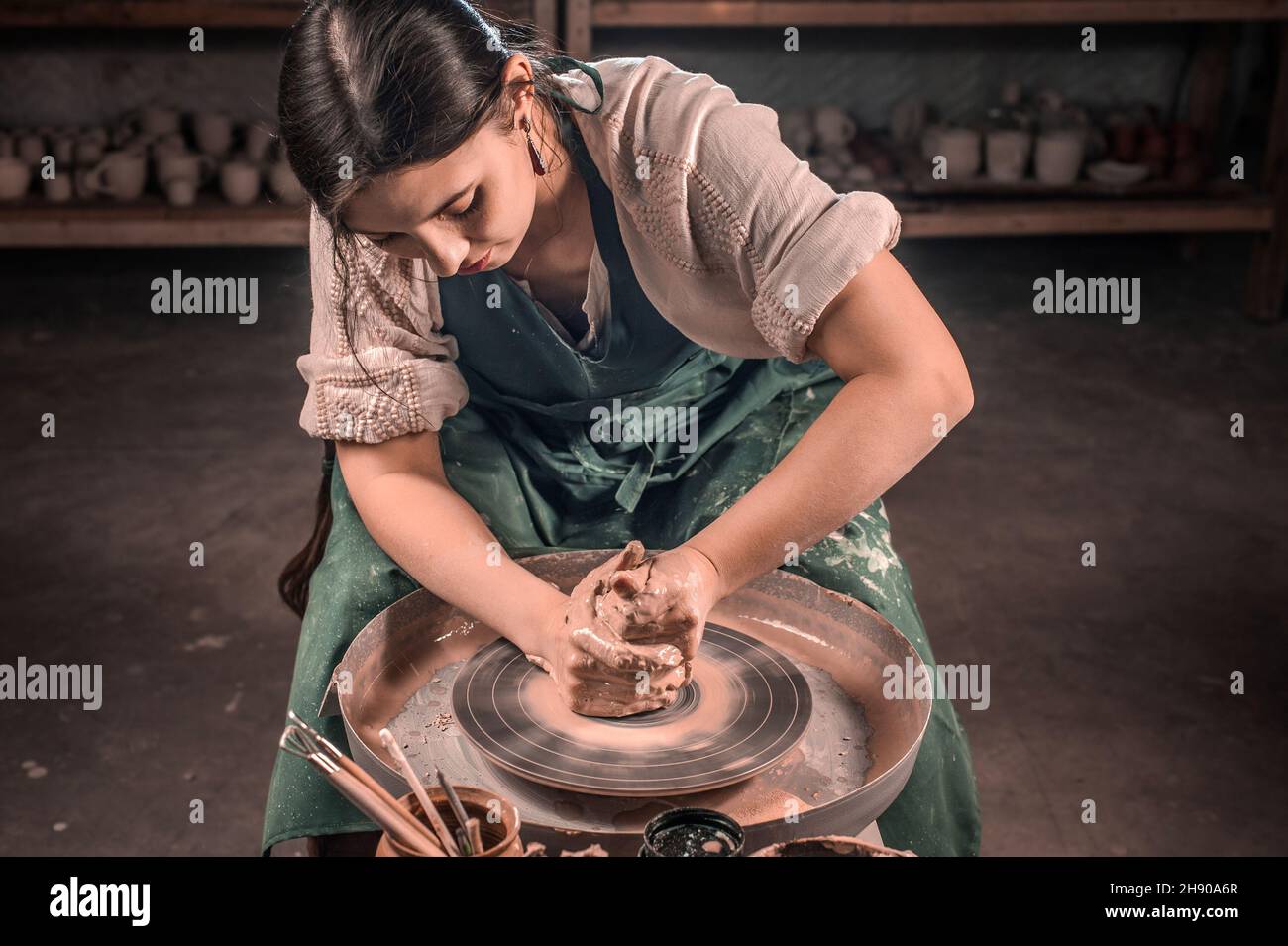 Stylish craftsman master making ceramic pot on the pottery wheel ...