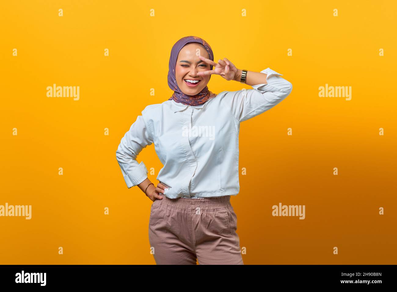 Portrait of cheerful Asian woman showing peace sign over eye over ...