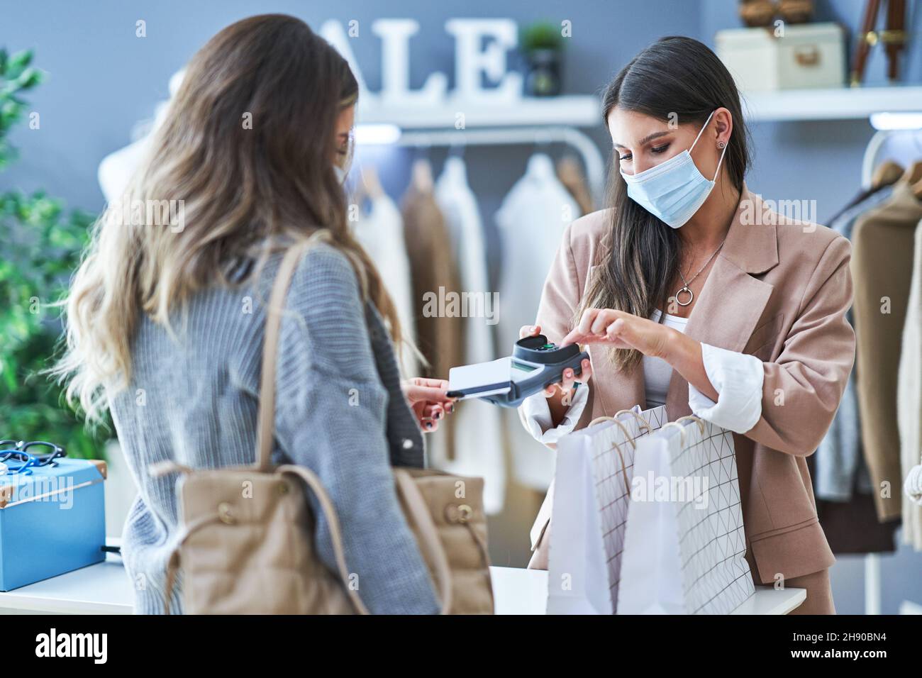 Woman seller and buyer in clothes store Stock Photo - Alamy