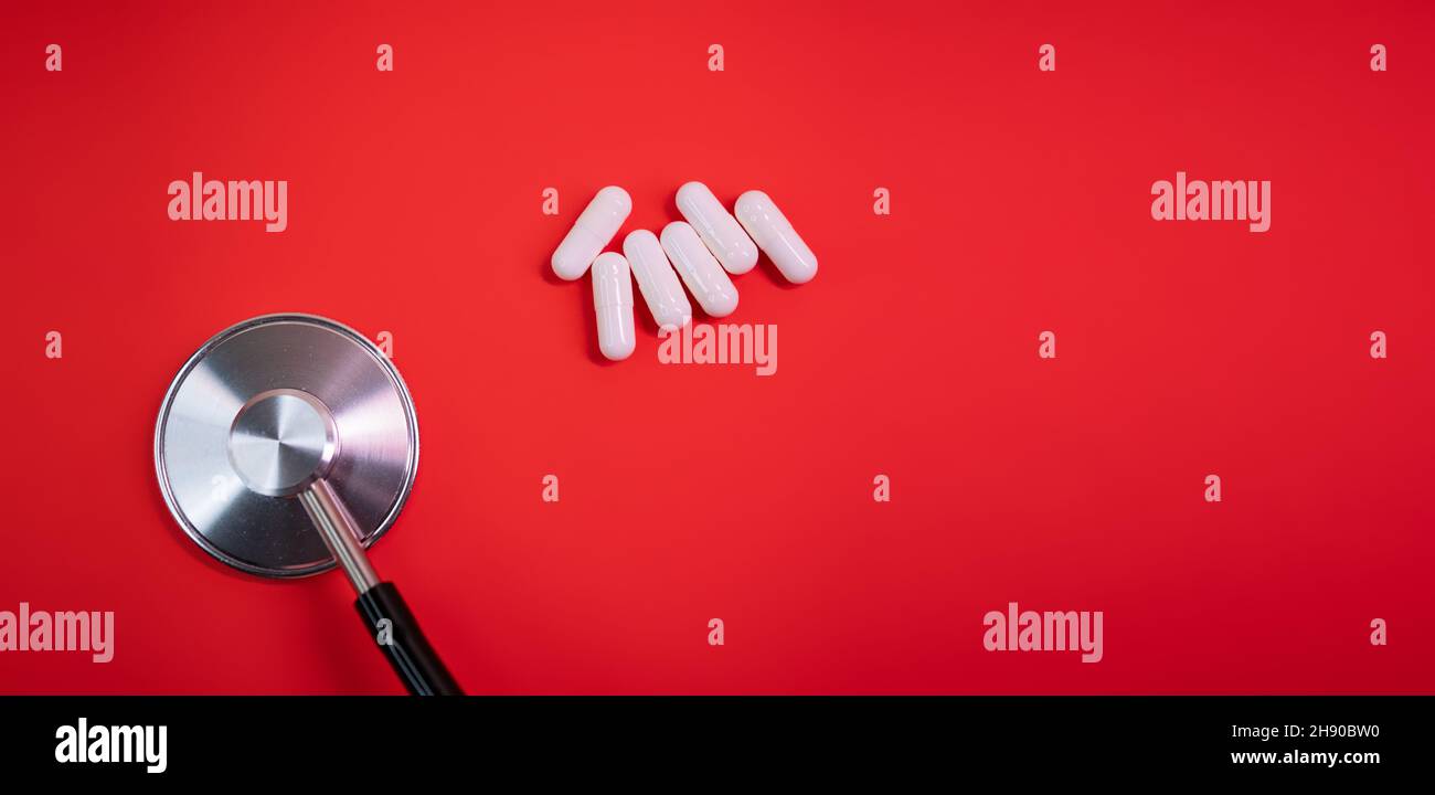 White drug capsules on colored red paper texture background. Macro ...