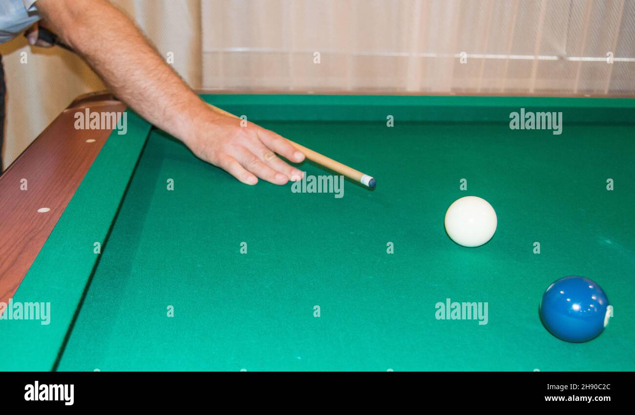 A close-up of a billiard table with balls pointing the athlete's hands ...