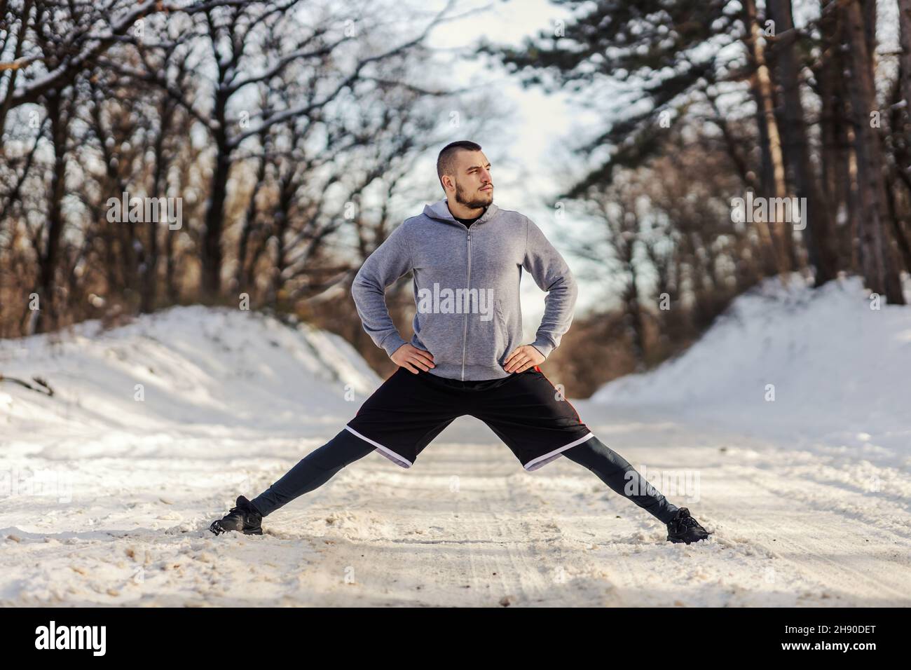 Sportsman doing splits and stretching exercises while standing in ...