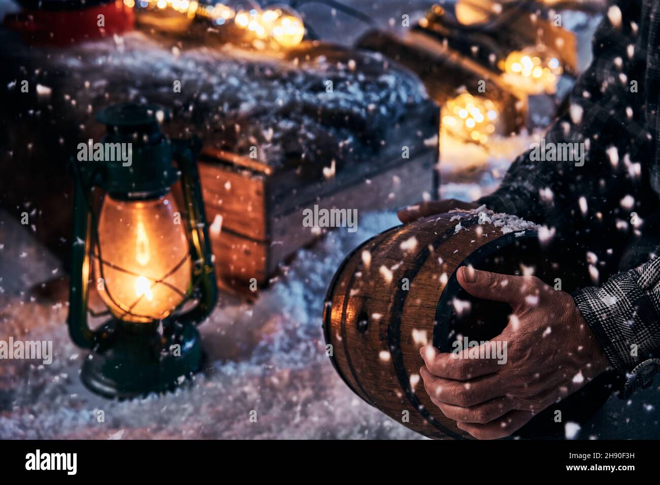 Crop faceless male holding wooden barrel with beer in snowy winter yard ...