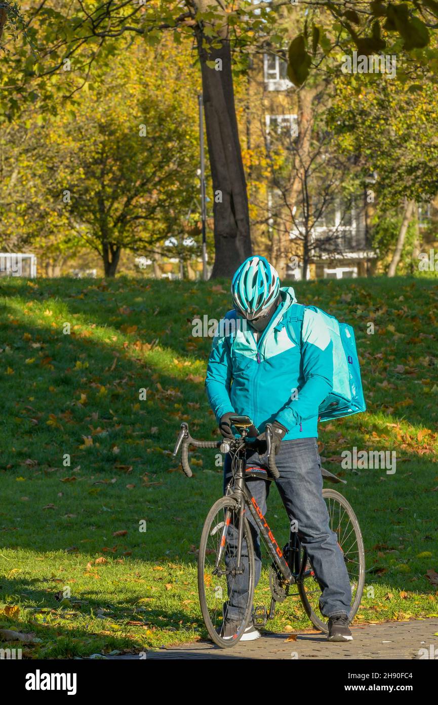 deliveroo cycle delivery person looking at application on smartphone ...