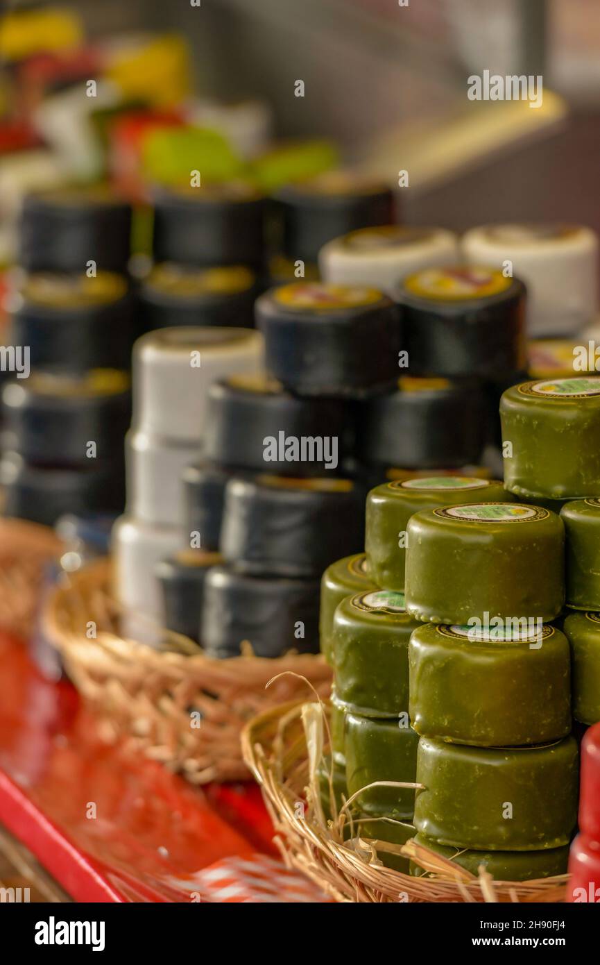 selection of waxed cheeses in red green and black wrappers on a stall ...