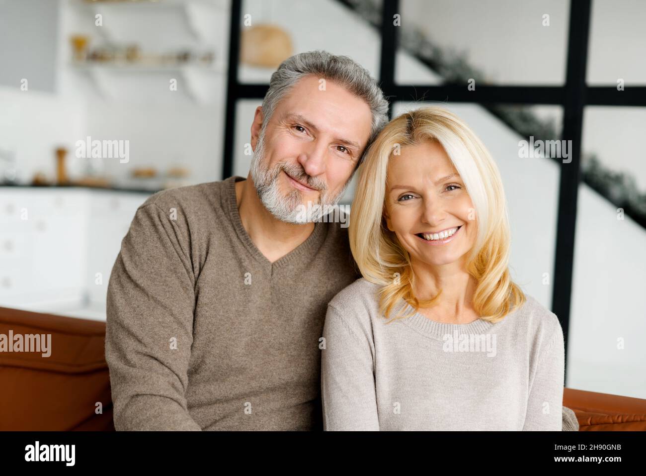Serene and carefree middle-aged couple in love looks at the camera and ...