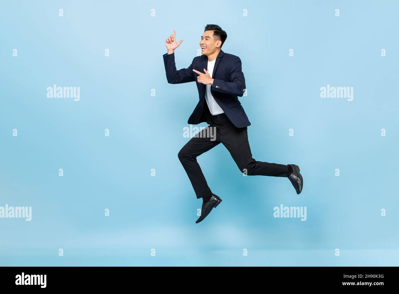 Full lenght portrait of smiling handsome Asian man jumping and pointing ...