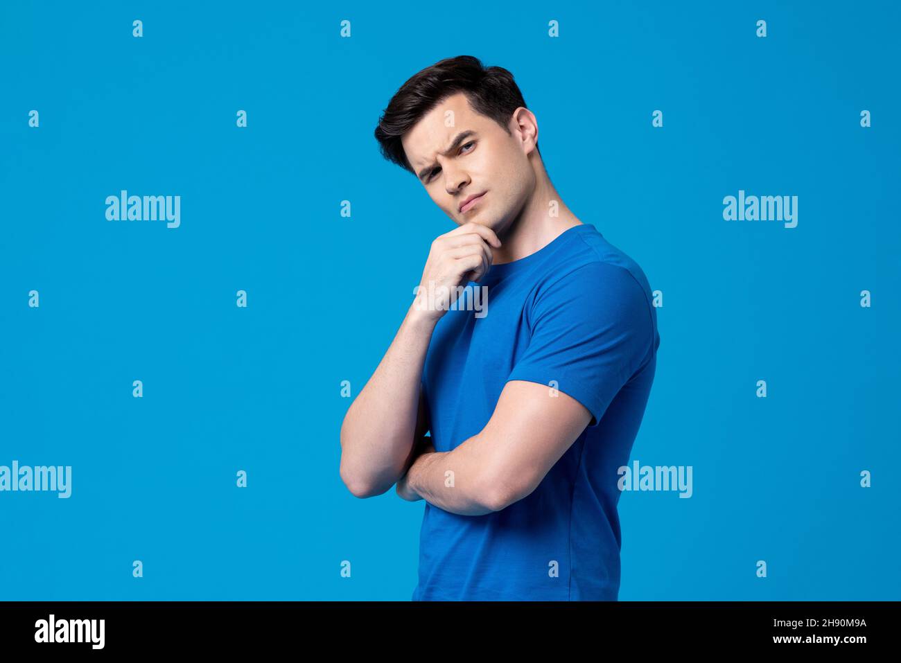 Young curious handsome Caucasian man thinking with hand touching chin ...