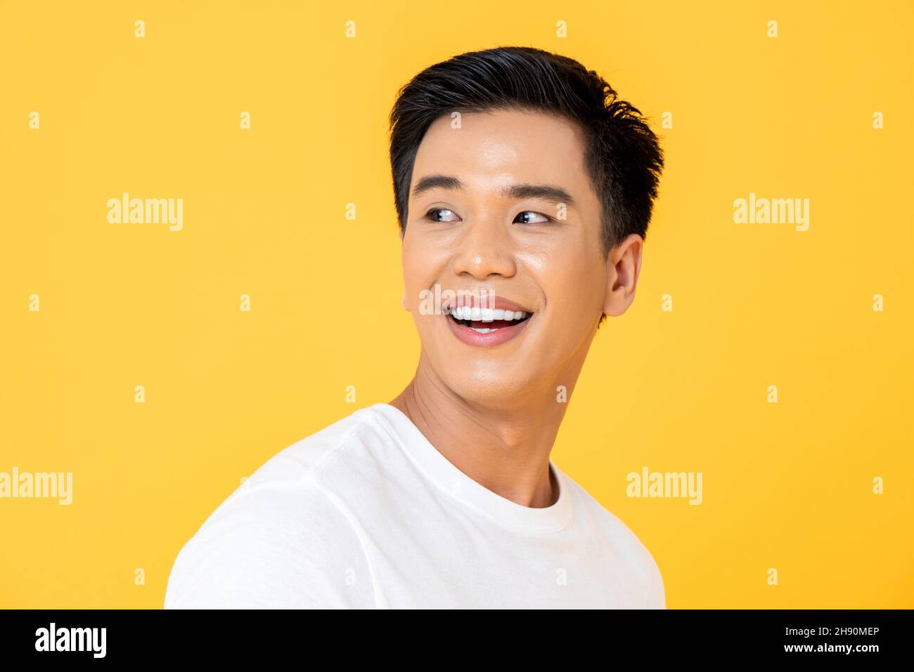 Young handsome smiling Asian man face in isolated yellow color ...