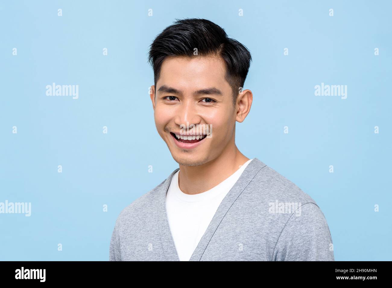 Young handsome smiling Asian man face in isolated light blue color ...