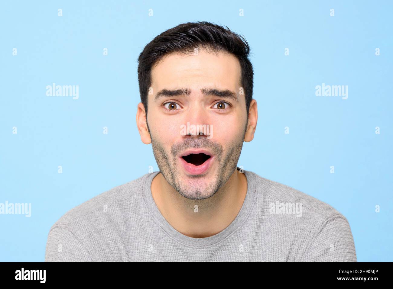 Surprised handsome Caucasian man gasping in isolated light blue studio ...