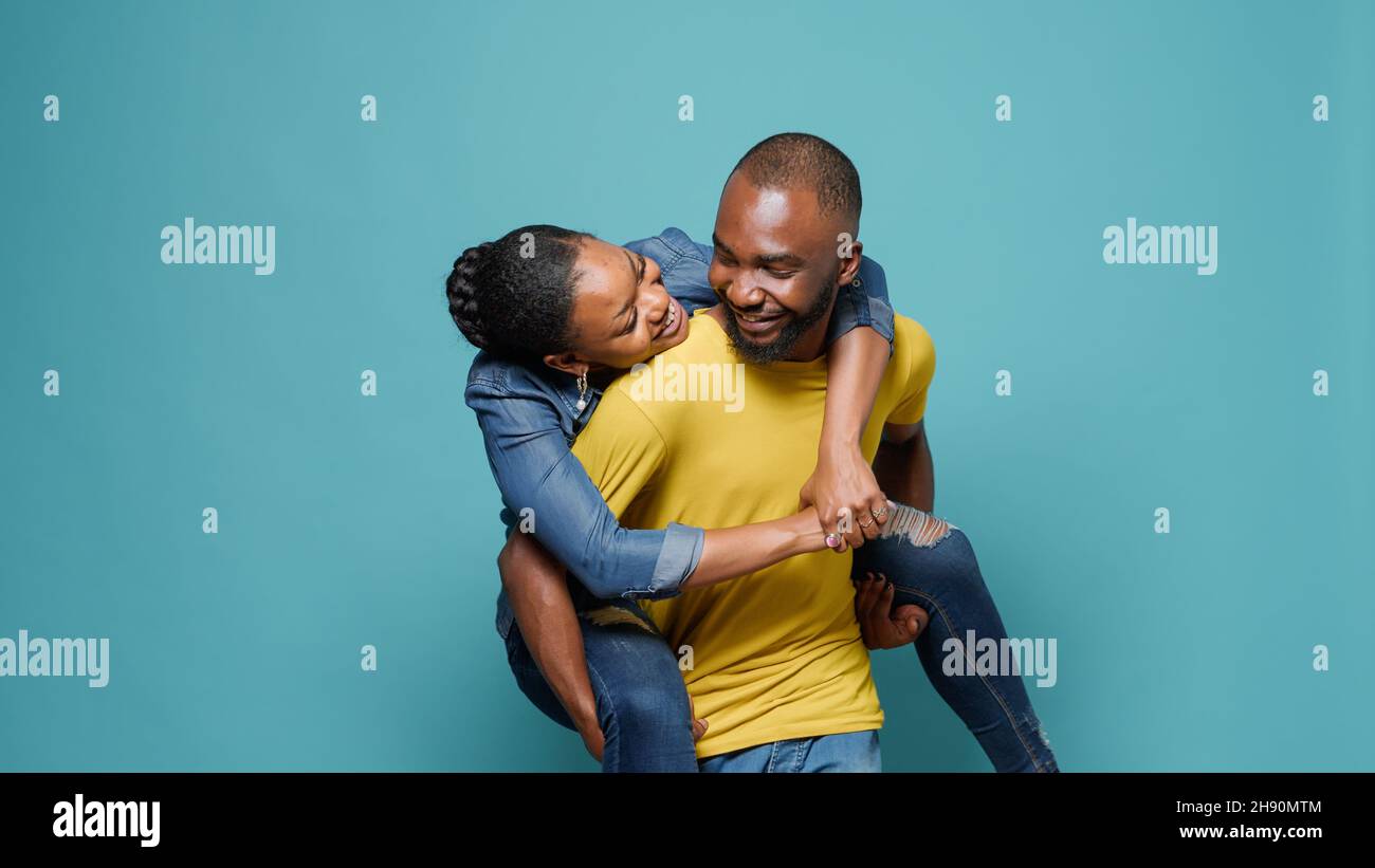 Playful couple having fun with piggy back ride in front of camera. Man ...