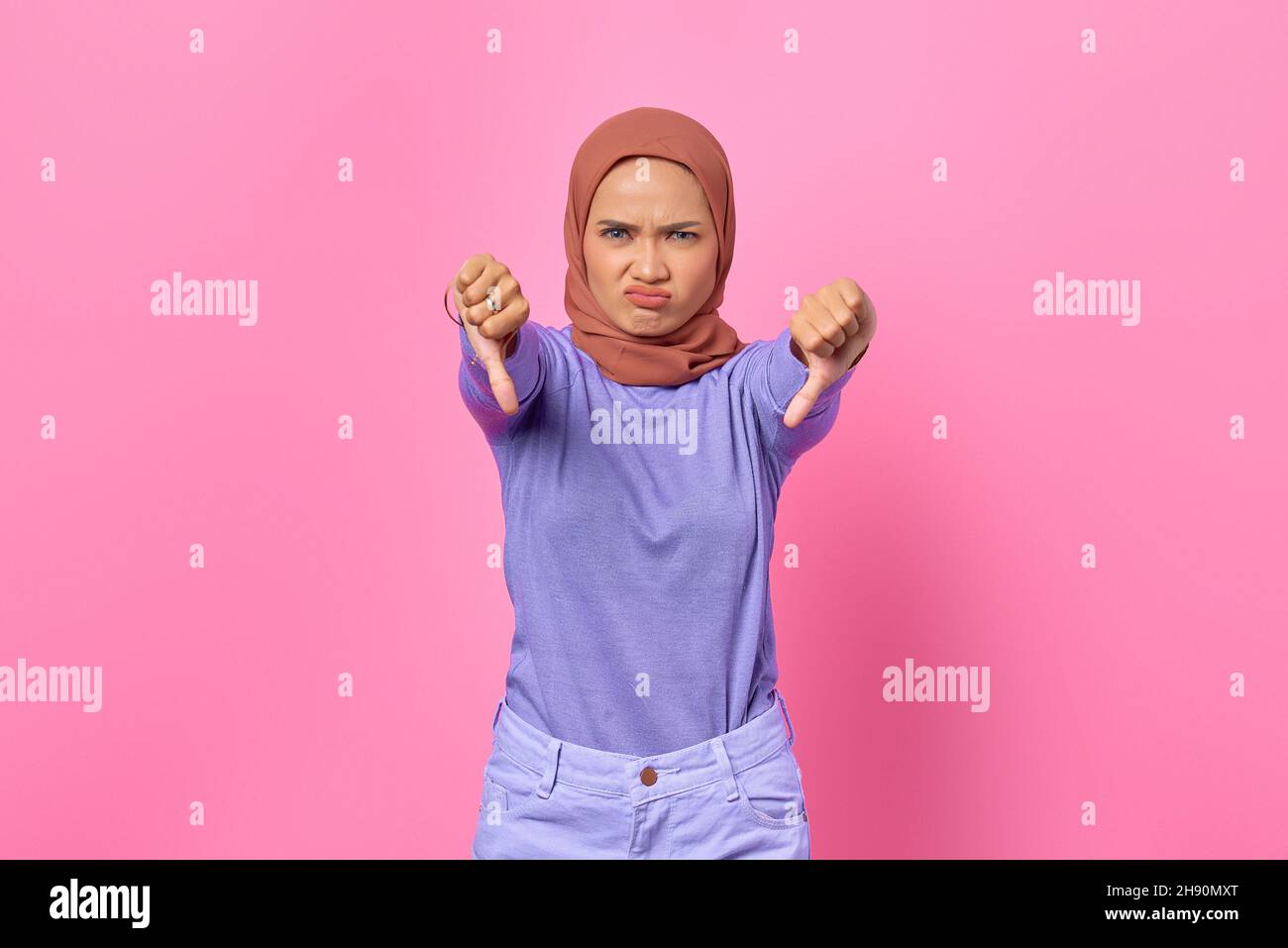 Angry young Asian woman showing rejection with thumbs down gesture on ...