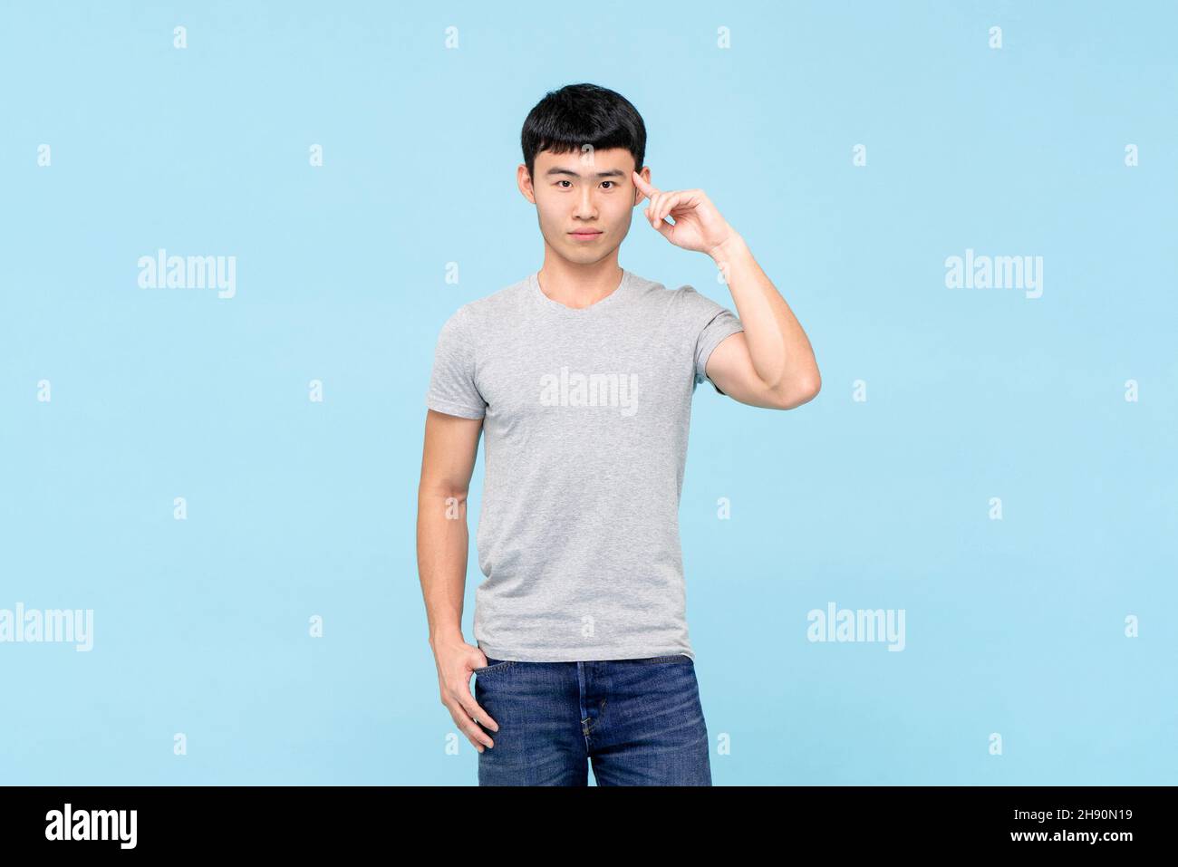 Young smart Asian man thinking with hand pointing on head in isolated ...