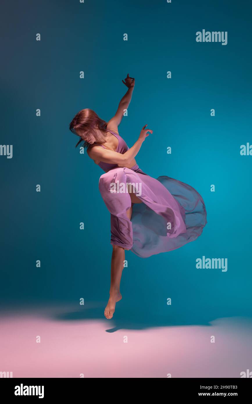 One young flexible contemp dancer in lilac dress dancing isolated on ...