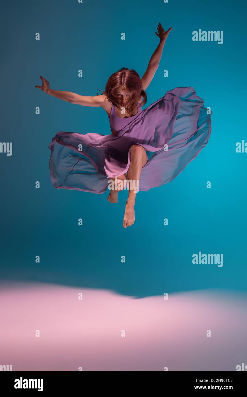 One young flexible contemp dancer in lilac dress dancing isolated on ...