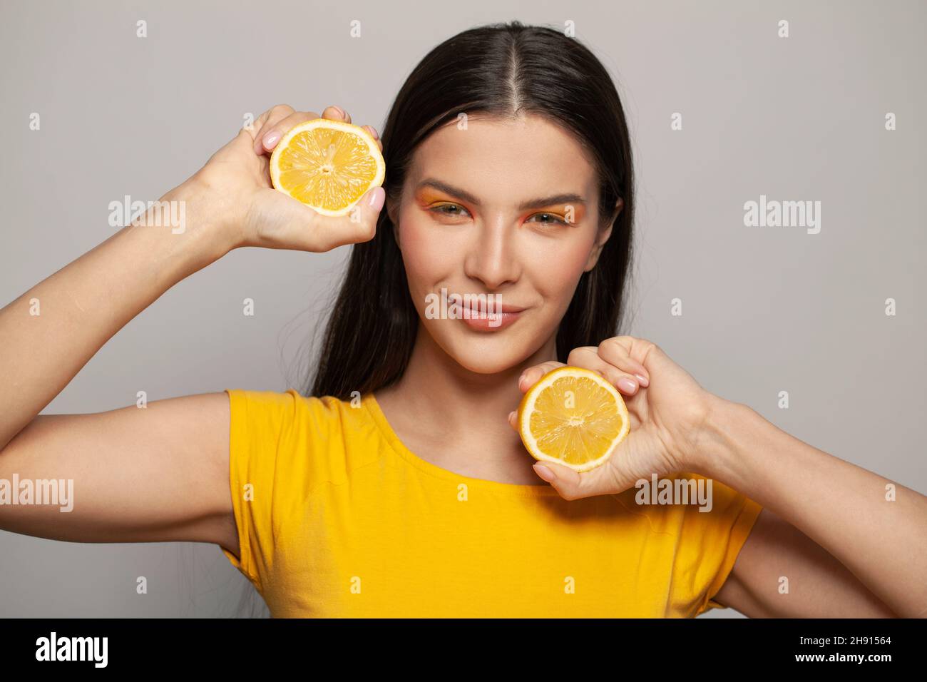 Portrait of attractive woman in yellow t-shirt with lemon fruits ...