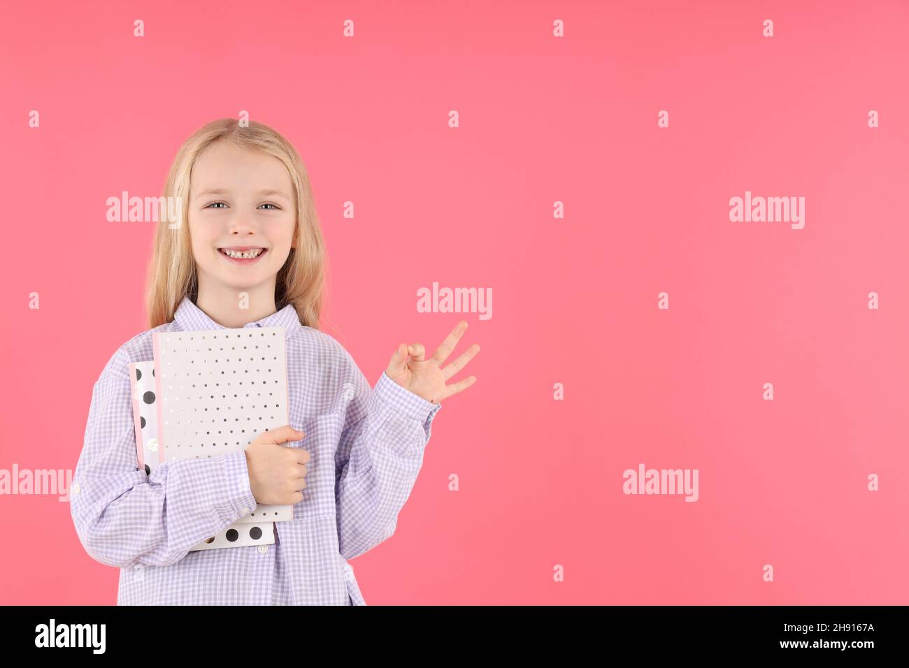 Cute little girl with notebooks on pink background Stock Photo - Alamy