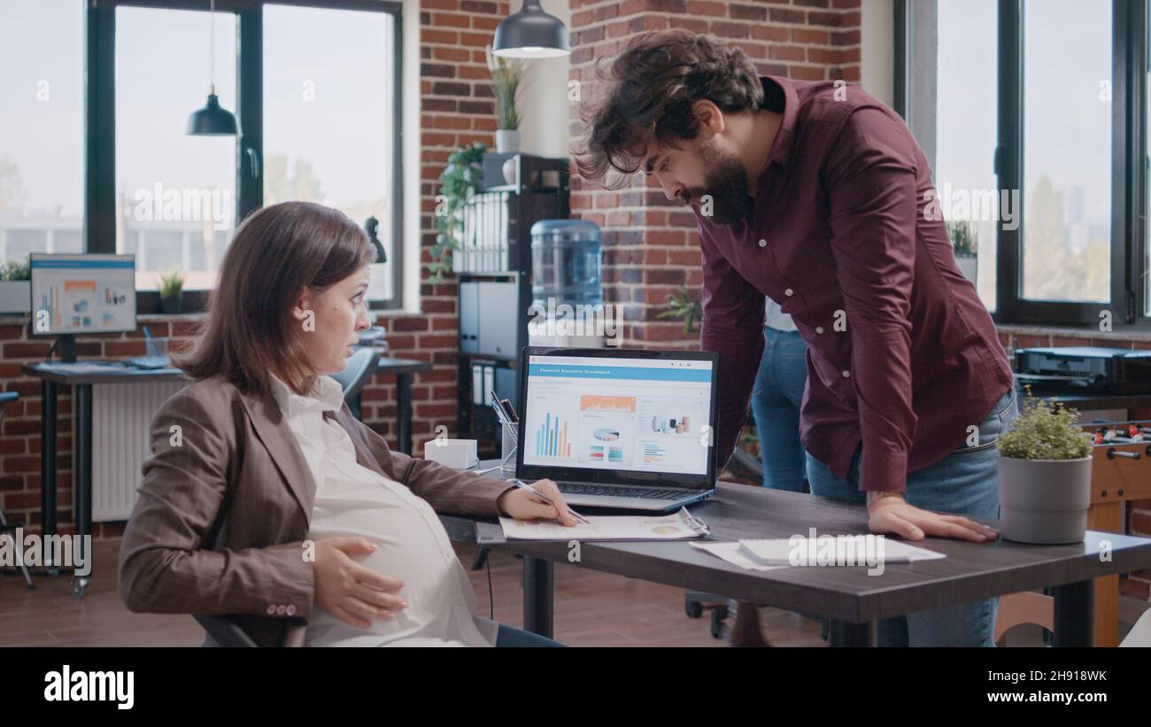 Business woman expecting child, working on analysis with colleague for ...
