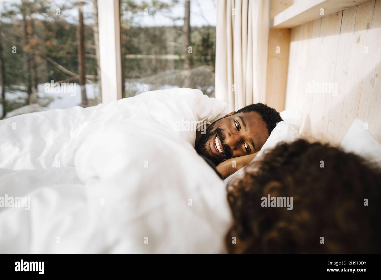 Smiling man lying with girlfriend on bed in cottage Stock Photo - Alamy